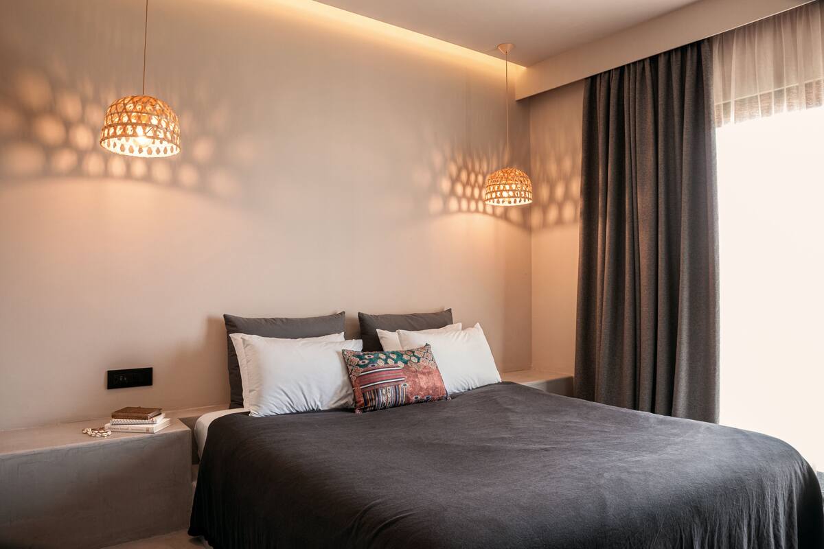 Um quarto moderno com uma cama grande, duas mesas de cabeceira e uma mesinha de apoio.