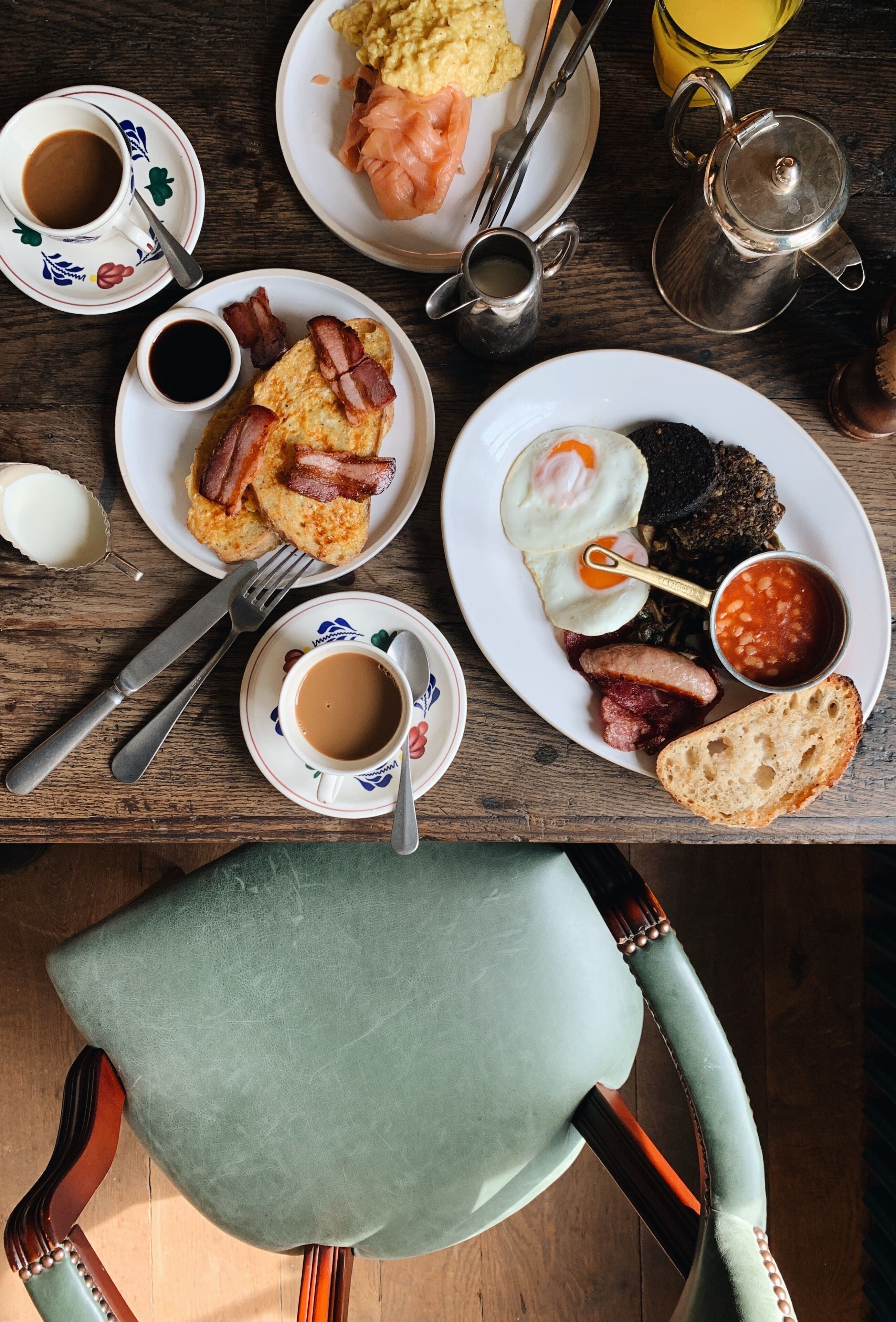 Uma mesa de café da manhã com pratos de ovos, bacon, torradas e café.