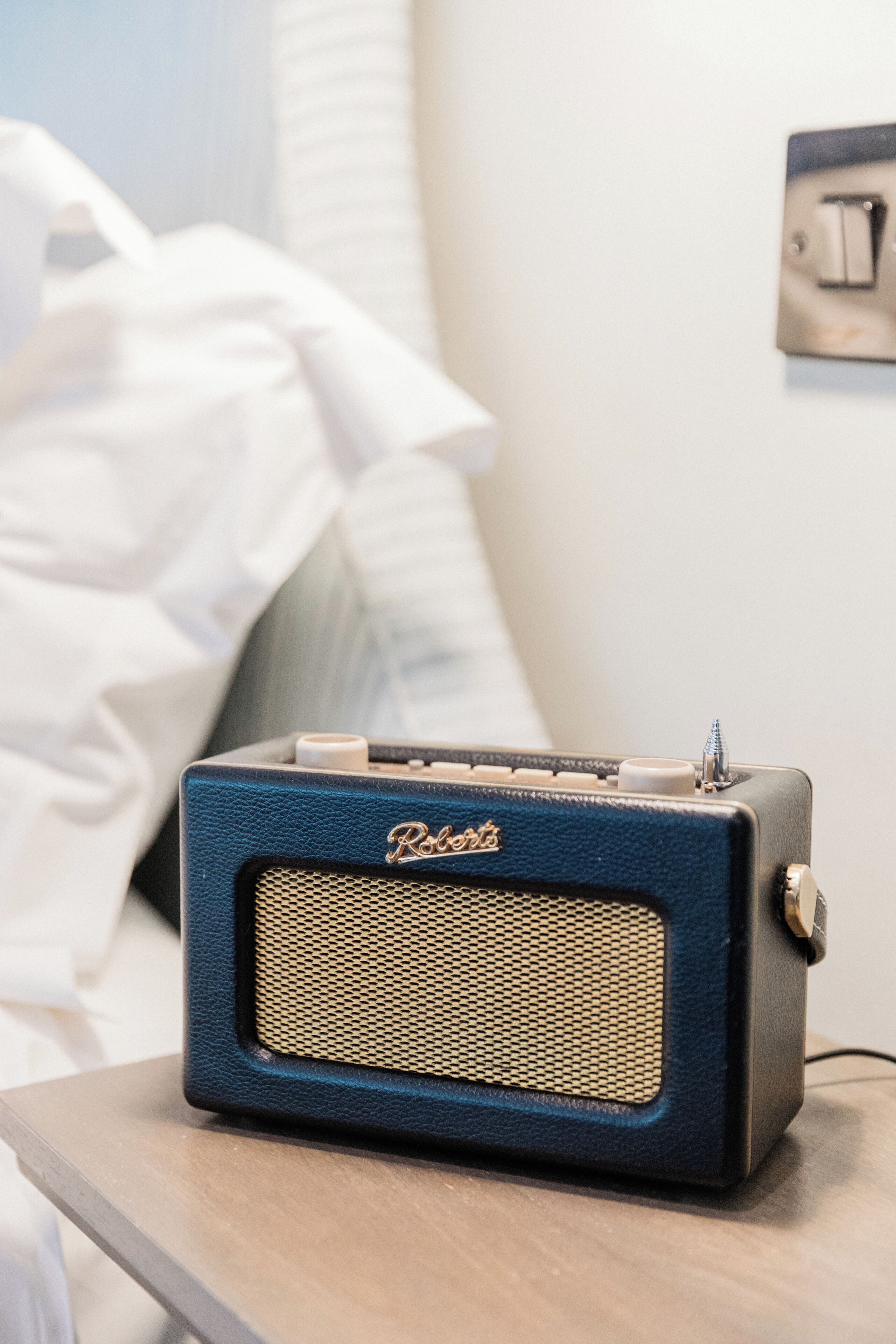 Um rádio de estilo vintage sobre uma mesa de cabeceira em quarto de hotel.