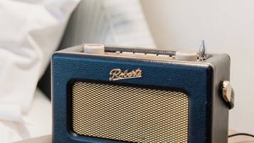 Um rádio de estilo vintage sobre uma mesa de cabeceira em quarto de hotel.