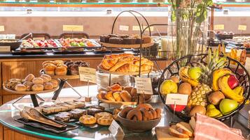 Buffet com diversos itens de comida, incluindo pastelaria, frutas e sobremesas.