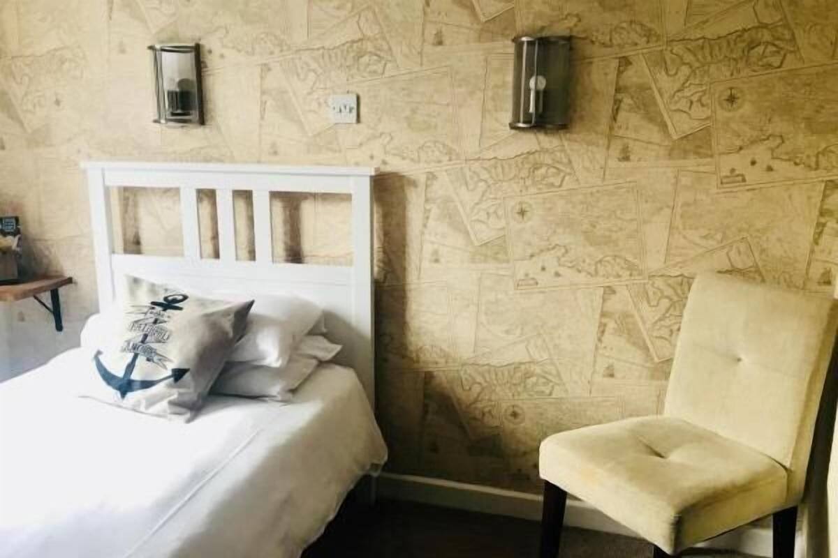 Quarto com cama, cadeira e papel de parede estampado.