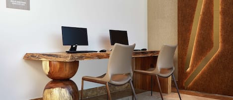 Um espaço de trabalho com dois computadores, duas cadeiras, uma mesa de madeira e piso de mármore.