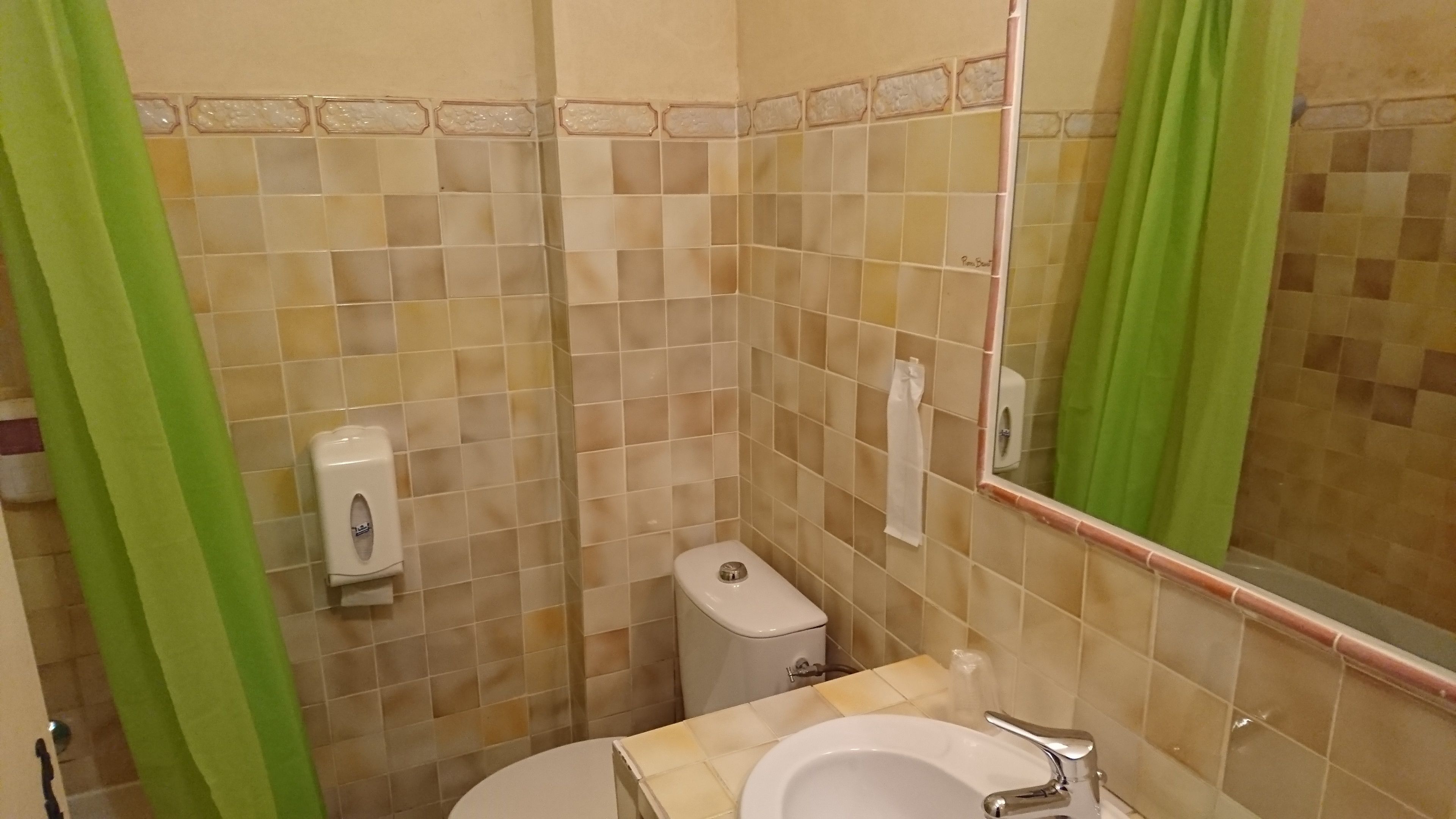 Casa de banho com sanita, lavatório e dispensador de sabonete líquido.