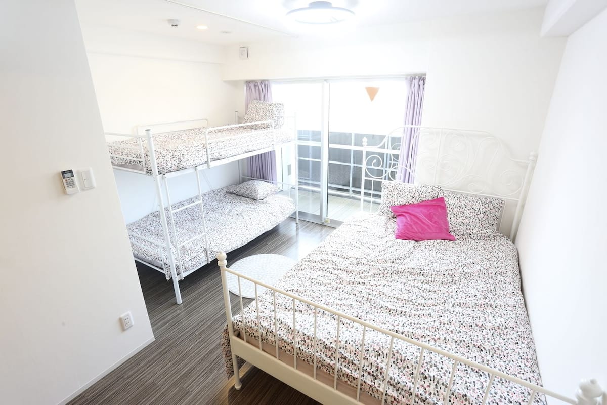 Quarto de hotel com beliche, uma cama de solteiro e varanda com vista.