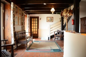 Um interior tradicional com móveis de madeira, escada e um porta-chapéus suspenso.