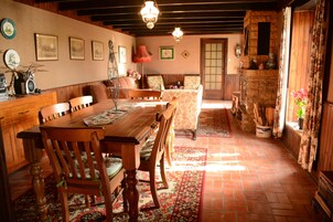 Uma sala de jantar tradicional com mesa e cadeiras de madeira, um sofá e uma lareira.