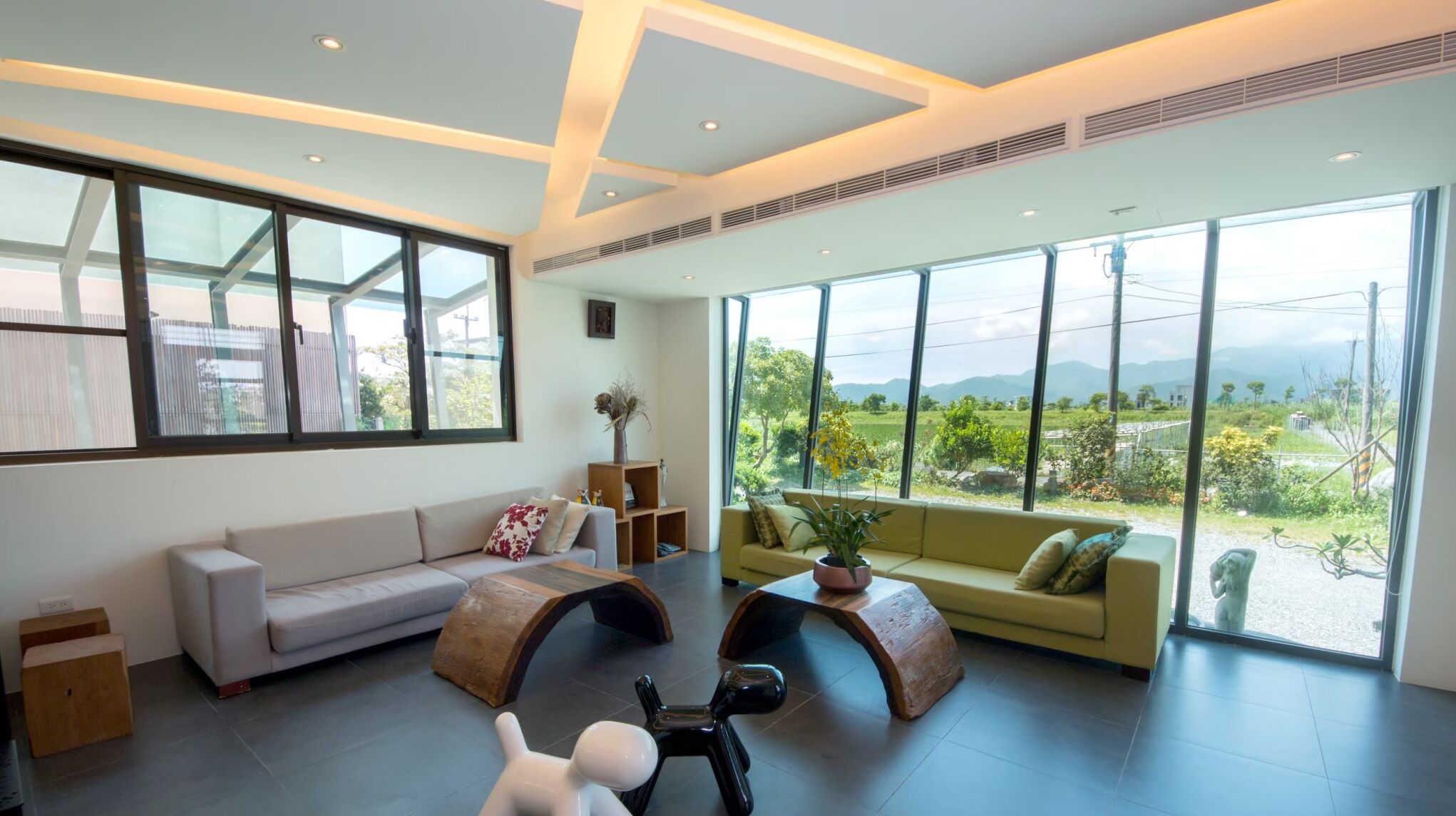Uma sala de estar moderna com uma janela grande, um sofá, uma mesa de centro e uma escultura decorativa.
