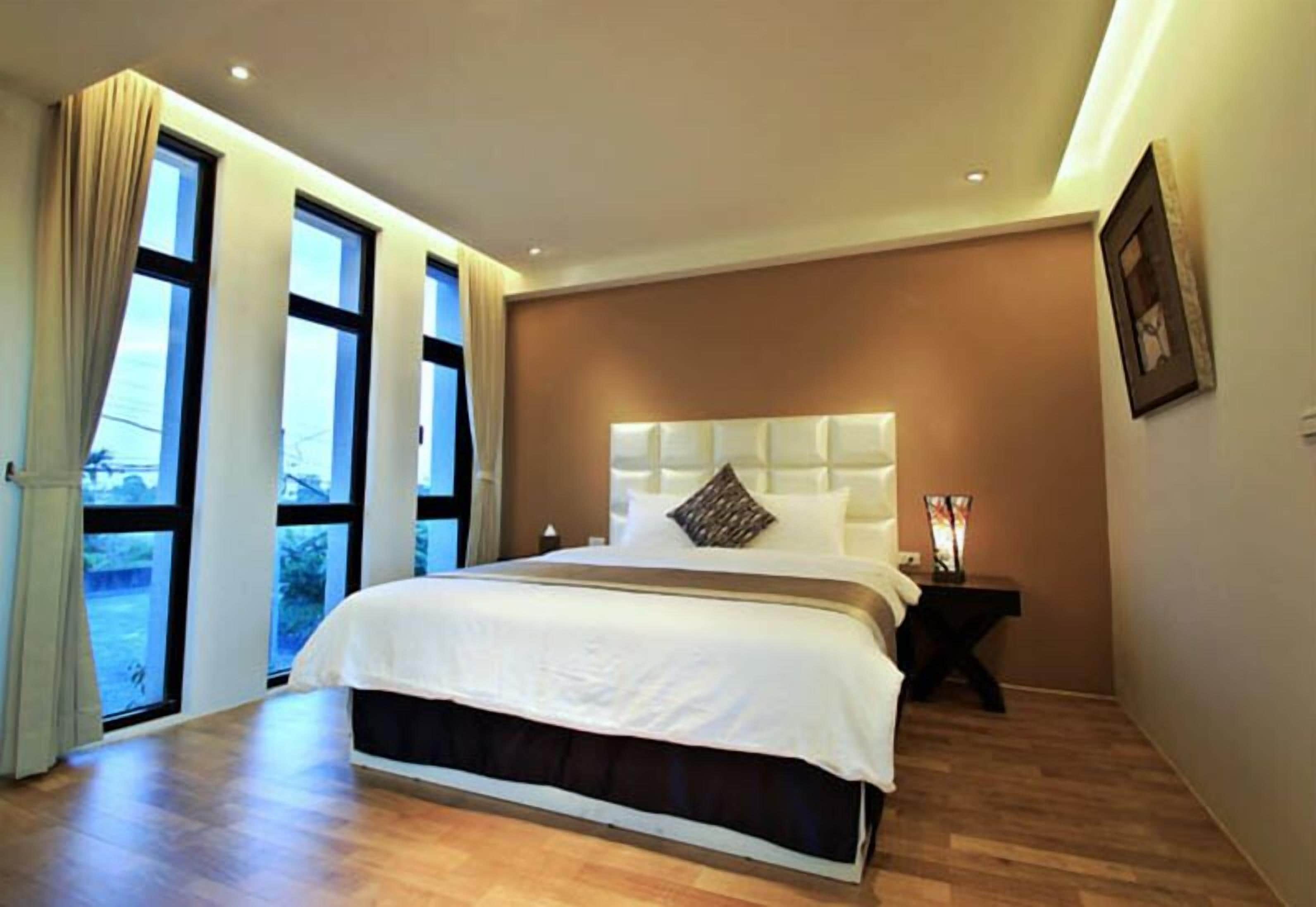 Quarto moderno com uma cama grande, cabeceira e mesa de cabeceira com abajur.