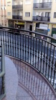 Varanda com guarda-corpo de metal e vista para a rua.