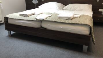 Uma cama bem arrumada com cabeceira de madeira, roupa de cama branca e um edredom verde com padrão.