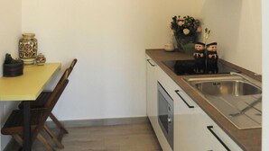 Uma cozinha compacta com uma mesa de jantar de madeira, forno embutido e uma pia de aço inoxidável.