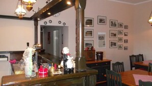 Um interior de restaurante acolhedor, com área de bar, móveis de madeira e quadros nas paredes.