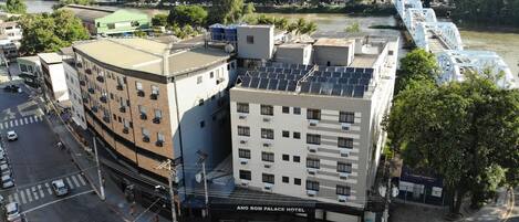 Um hotel com telhado plano, painéis solares e uma placa com a inscrição "ANO BOM PALACE HOTEL".