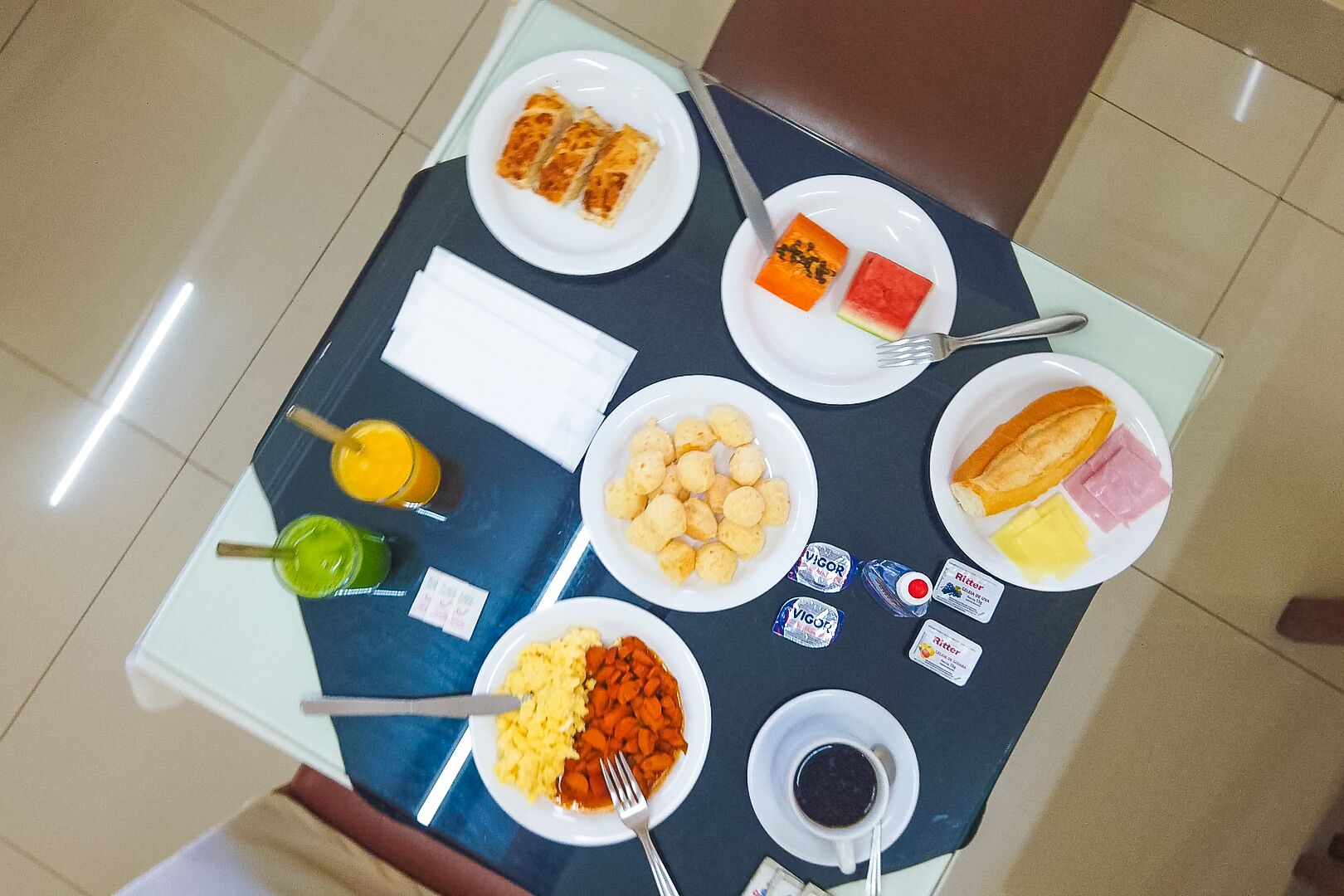 Uma mesa de jantar com vários itens de café da manhã, incluindo torradas, frutas e uma xícara de café.