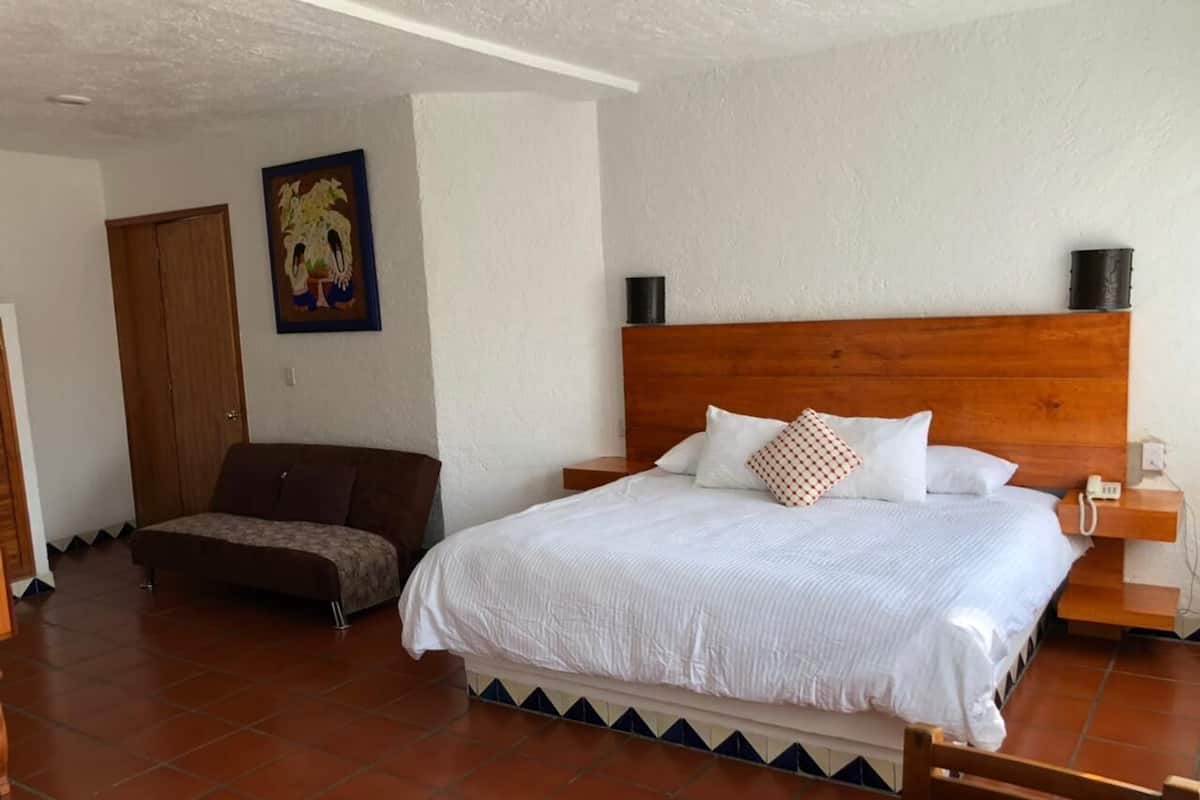 Quarto com uma cama grande, um sofá, uma cabeceira de madeira e um quadro na parede.