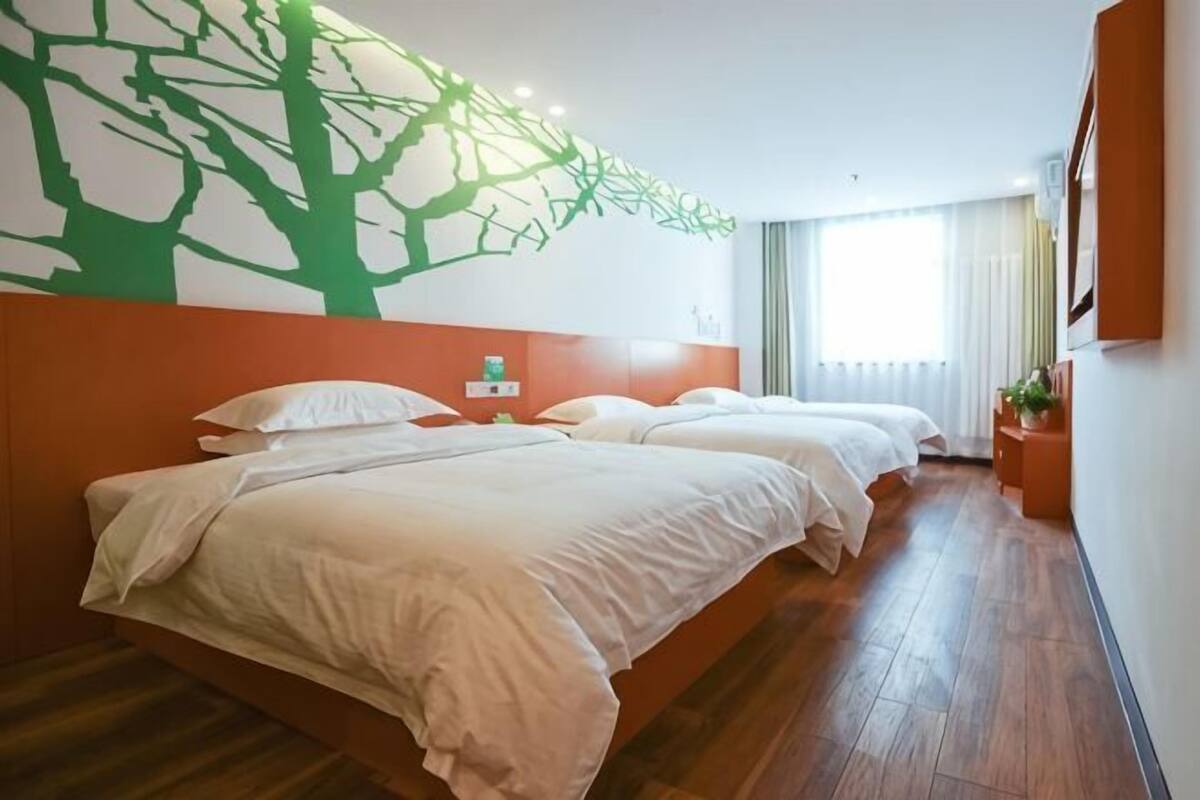 Quarto de hotel com duas camas, um mural grande na parede, uma janela e piso de madeira.
