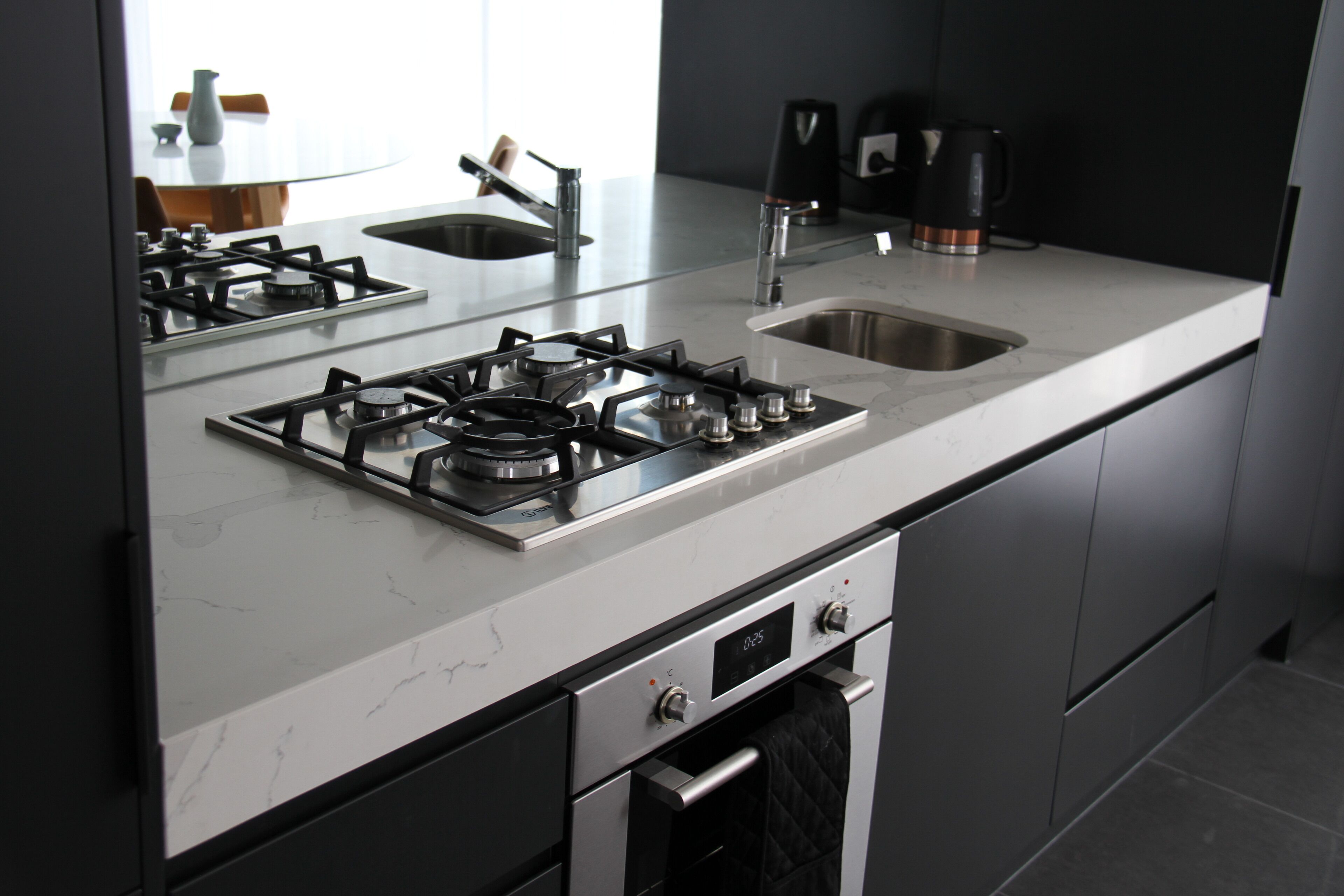 Cozinha moderna com fogão a gás, pia de aço inoxidável e máquina de café.