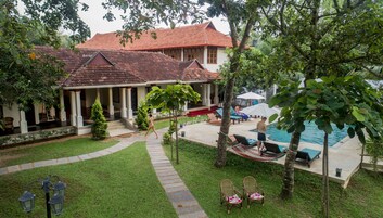 Uma casa com telhado de telhas, piscina e jardim com caminho.