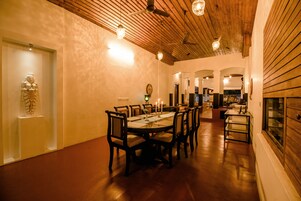 Uma sala de jantar com teto de madeira, uma mesa redonda com cadeiras e vista para outro espaço.