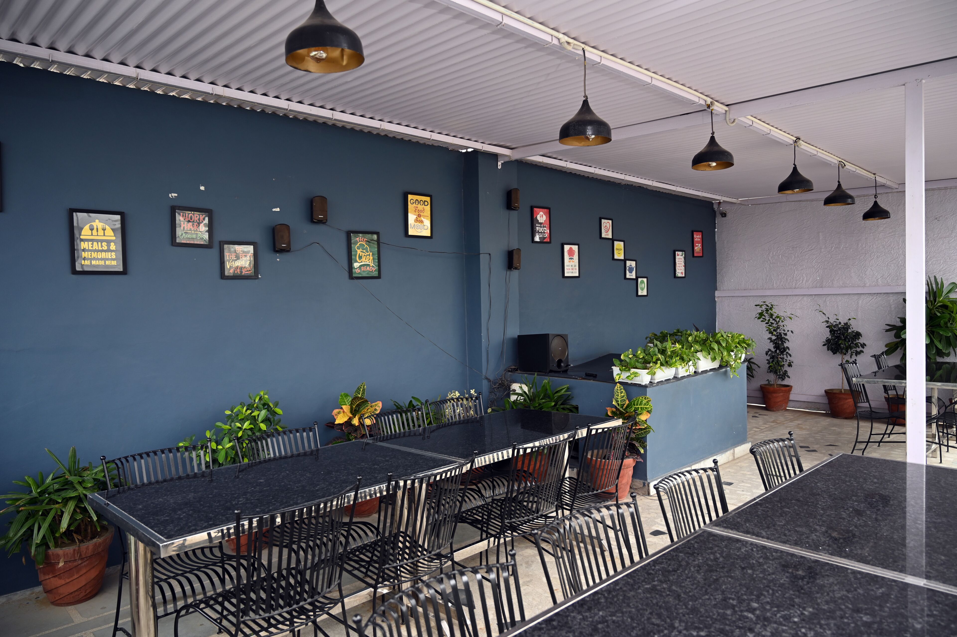 Uma sala de jantar com uma mesa comprida, cadeiras pretas e luminárias pendentes.