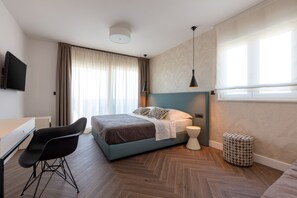Quarto moderno com cama, escrivaninha, cadeira, sanita e um pequeno banquinho.