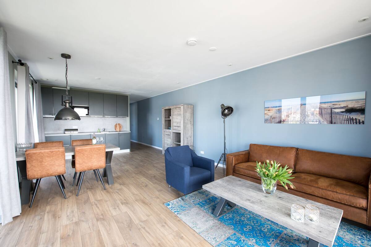 Uma sala de estar moderna com um sofá marrom, uma mesa de centro e uma poltrona azul.