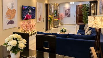 Uma sala de estar moderna com um sofá azul, televisão, obras de arte e lareira.