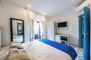 Quarto de hotel com uma cama, televisão, guarda-roupa e porta de banheiro.