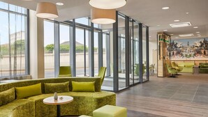 Um hall moderno com sofá verde, mesa redonda e portas de vidro que dão para o exterior.