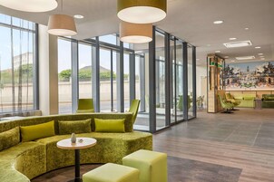 Um hall moderno com sofá verde, mesa redonda e portas de vidro que dão para o exterior.