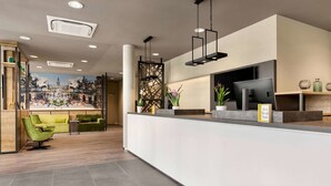 Uma área de recepção moderna com um balcão branco, assentos verdes e um mural com vista para a cidade.