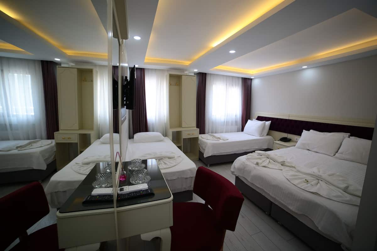 Quarto de hotel com duas camas, uma escrivaninha e um espelho.
