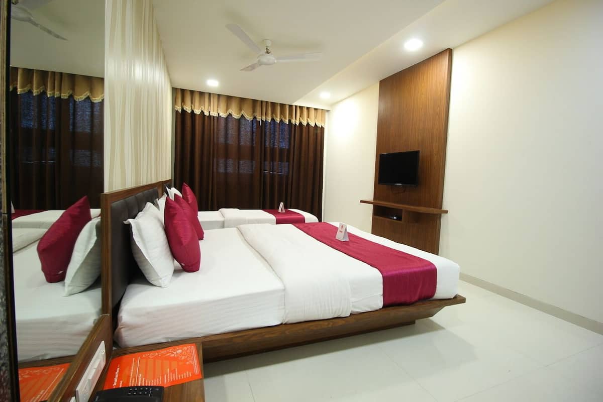 Quarto de hotel com uma cama grande, uma televisão de tela plana na parede e um ventilador de teto.