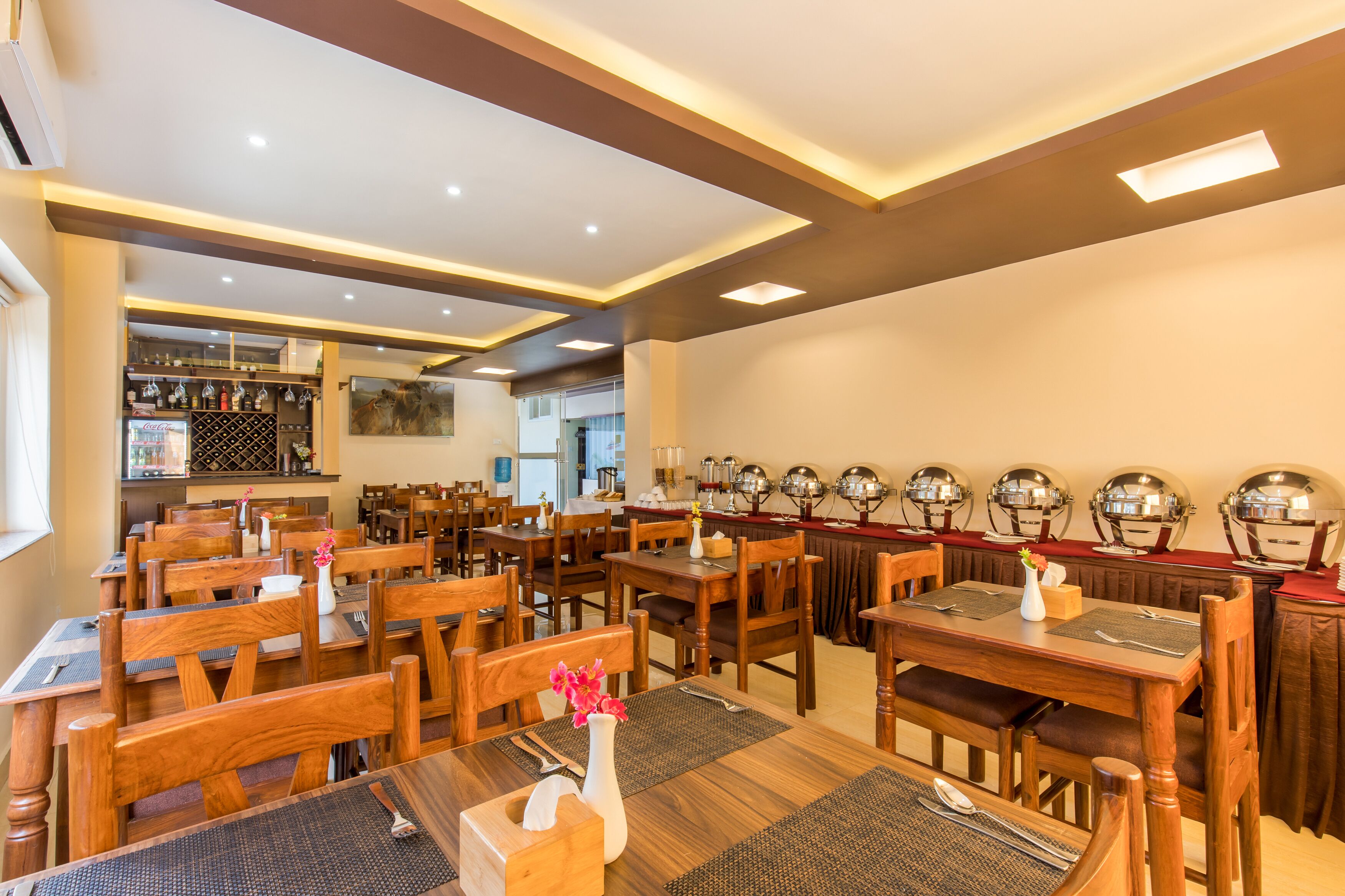 Um restaurante com mesas e cadeiras de madeira, um espaço de bar e globos decorativos na parede.