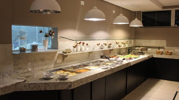 Uma cozinha moderna com bancada de mármore, vários pontos de preparo de alimentos e iluminação pendente.