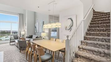 Quarto de hotel moderno com área de refeições, escada e vista para o exterior.