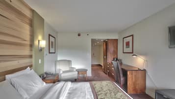 Quarto de hotel com cama, escrivaninha, cadeira, cômoda e televisão.