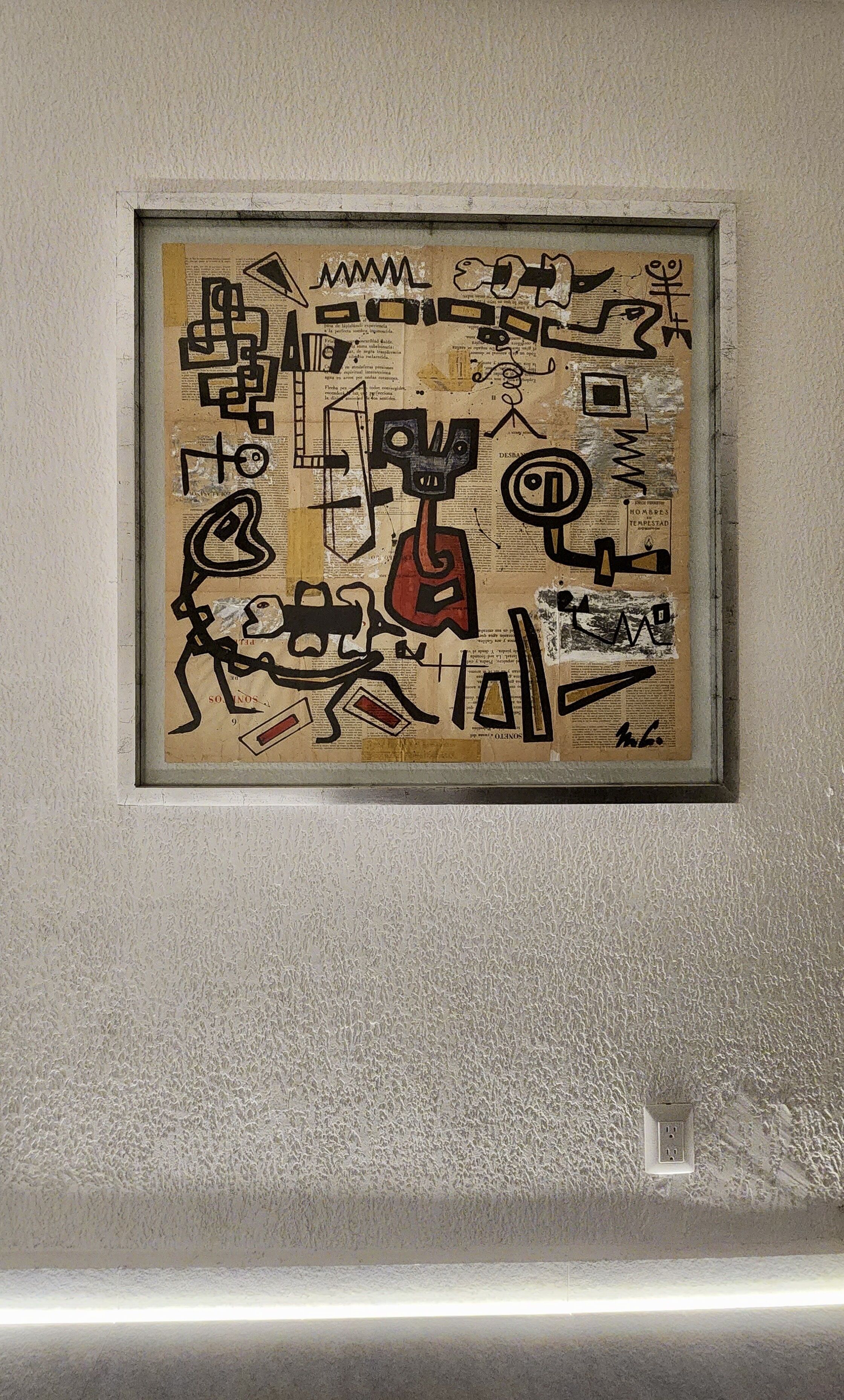 Obra de arte abstrata emoldurada numa parede texturizada.