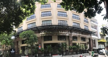 Fachada do Hotel Imperial Saigon com entrada curva, várias varandas e vegetação ao redor.
