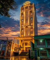 Um hotel com uma placa grande, vários andares e uma entrada bem iluminada.