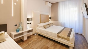 Quarto de hotel com uma cama grande, mesas de cabeceira e ar condicionado fixado na parede.