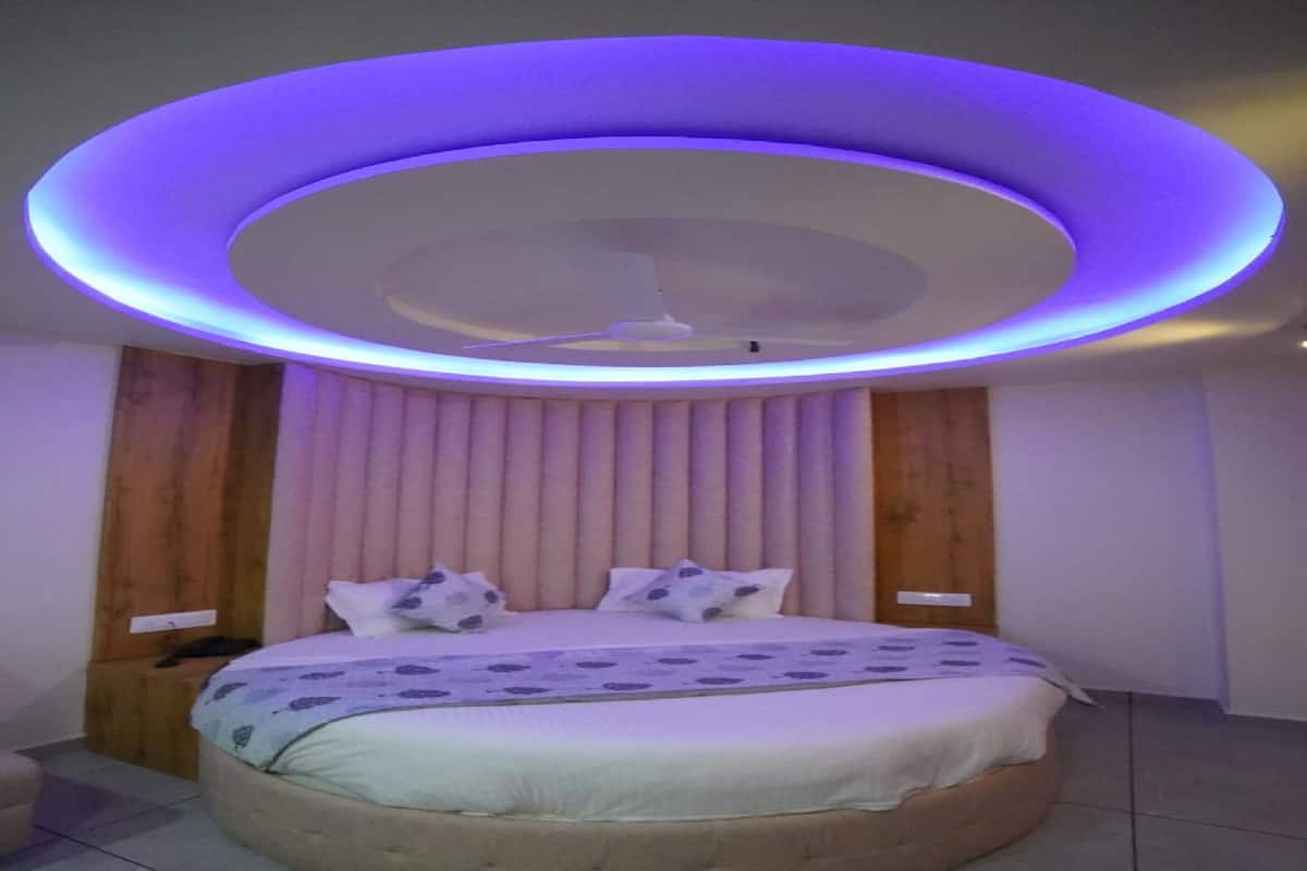Uma cama redonda com cabeceira circular, luminária no teto e painel de parede de madeira.