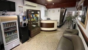 Um saguão com balcão de recepção, máquina de vendas automática, área de estar e escada.