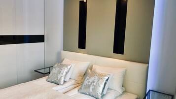Quarto moderno com uma cama grande, duas mesas de cabeceira e um guarda-roupa.