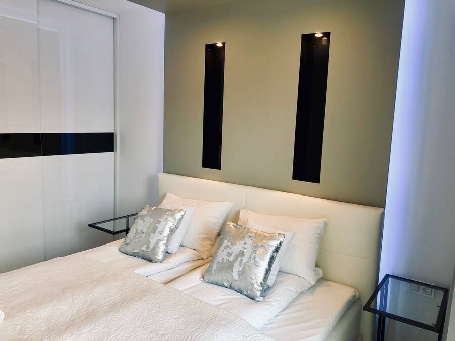 Quarto moderno com uma cama grande, duas mesas de cabeceira e um guarda-roupa.