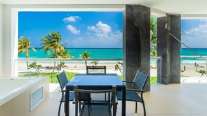 Varanda com vista para a praia, uma mesa com cadeiras e uma janela grande.