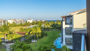 Resort com vários edifícios, piscina e palmeiras.