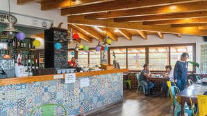 Um restaurante com teto de madeira, paredes azulejadas e cadeiras coloridas.