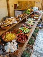Buffet com diversas opções de comida, incluindo pão, carnes, queijos e legumes.